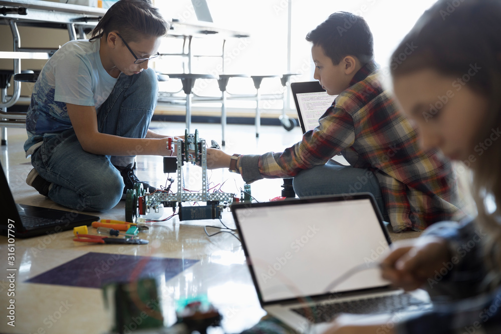 Pre-adolescent boys assembling and programming robotics on classroom ...
