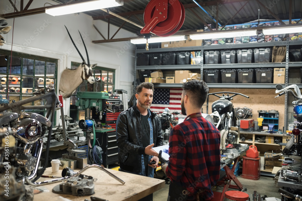 Motorcycle mechanics talking in auto repair shop Stock Photo | Adobe Stock