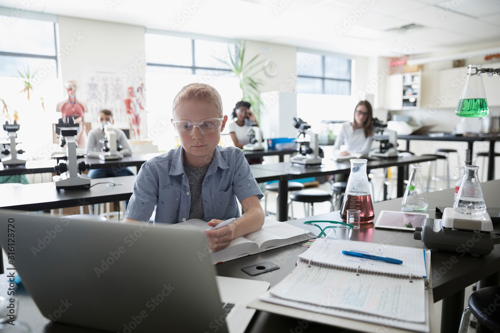 Boy middle school student conducting scientific experiment at laptop in ...