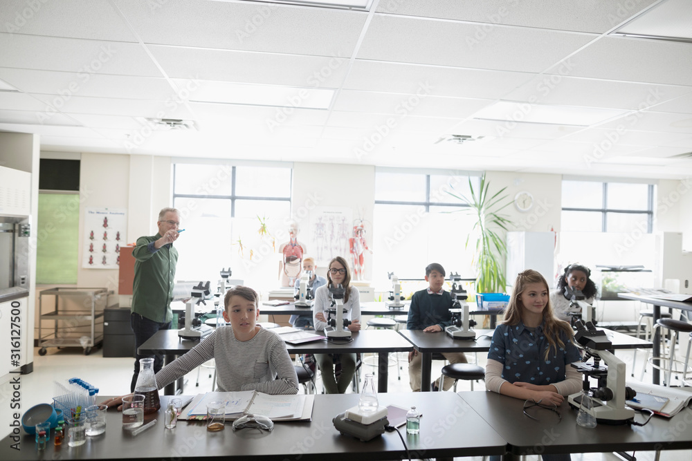 Students listening to teacher leading lesson in science laboratory ...