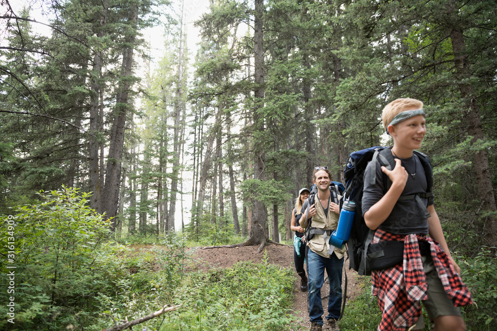 Smiling teenage boy outdoor school student hiking in woods below trees ...