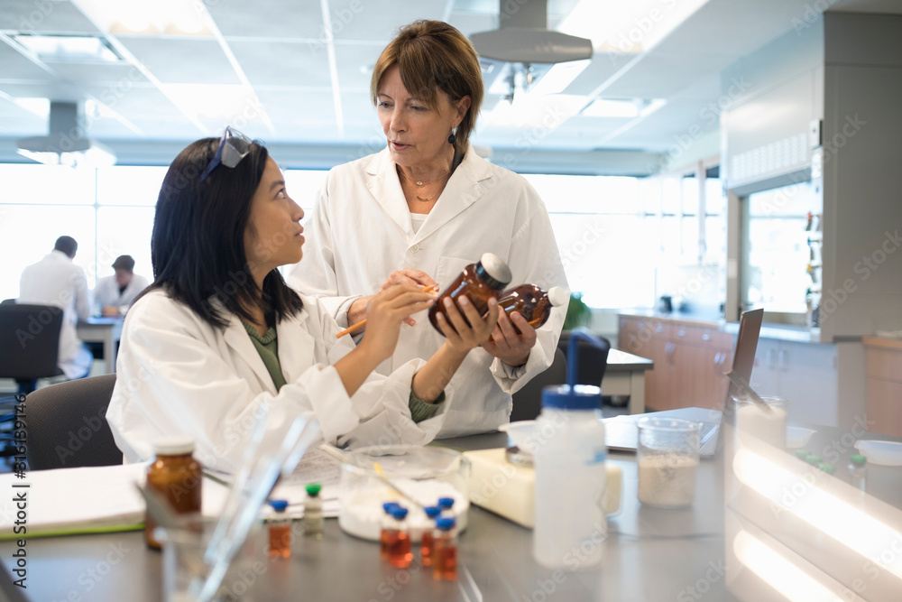 Female professor and college student conducting chemistry scientific ...