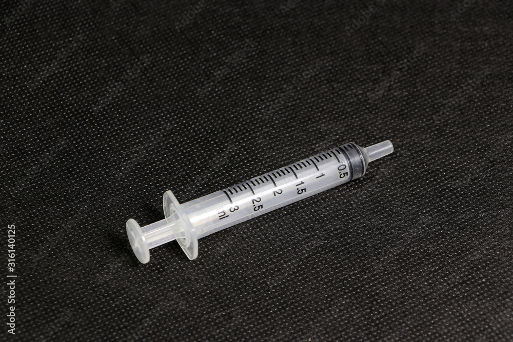 A syringe on black floor. It is simple reciprocating pump consisting of ...