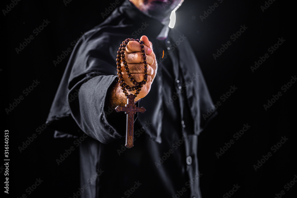 The priest holds the cross on black background For Halloween concepts ...
