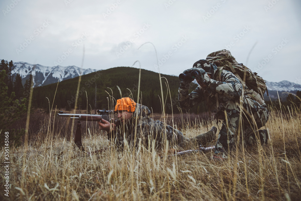 Male hunter friends scoping, using hunting rifle scope and binoculars ...
