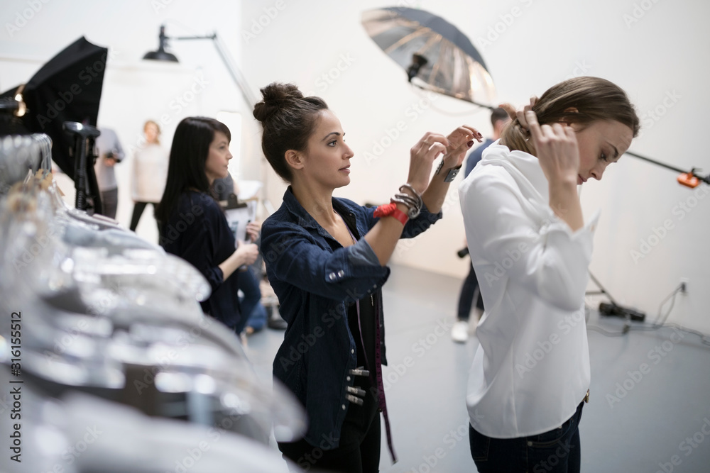 Female wardrobe stylist helping model trying on blouse at photo shoot ...
