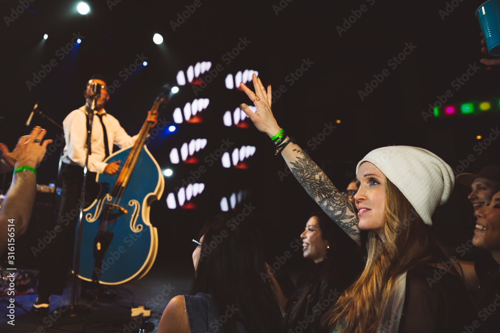 Female millennial dancing, cheering for musicians performing on stage ...
