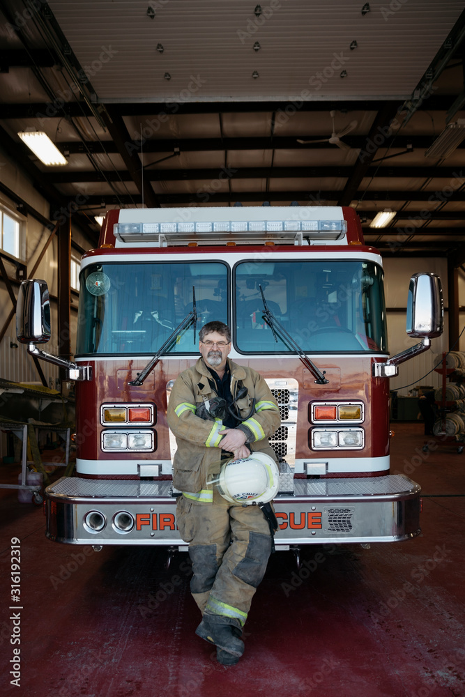 Portrait confident male firefighter standing in front of fire engine ...
