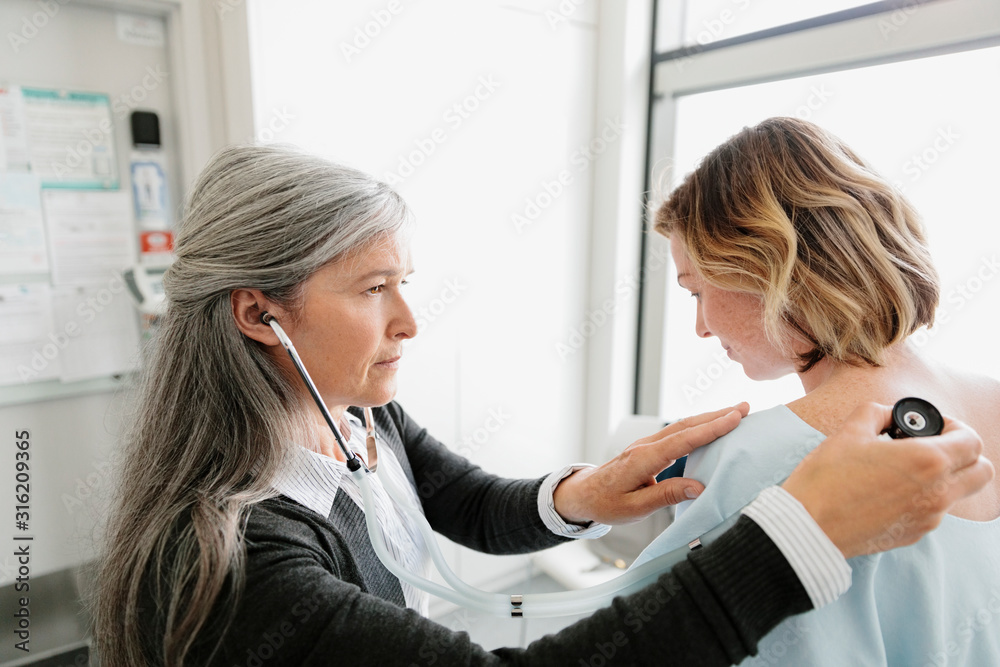 Female doctor with stethoscope examining woman in clinic examination ...