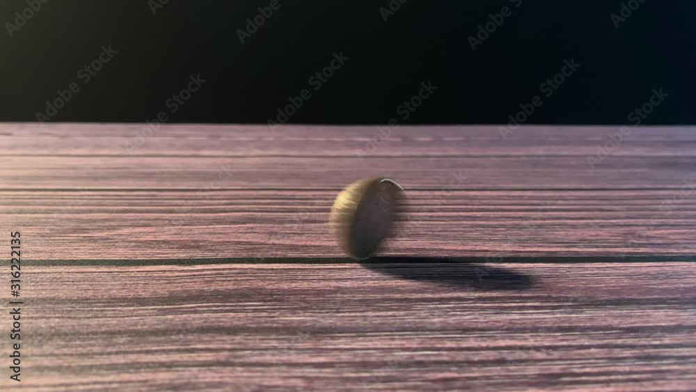 Coin flipping on the wooden table with a black background. One euro ...