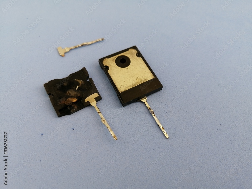 parts of an old broken bipolar transistor on a light blue background ...