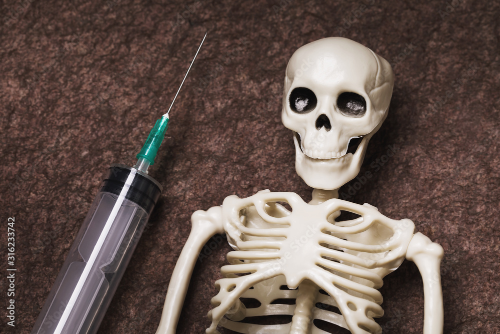 Human skeleton and syringe on a stone, top view. Lethal injection ...