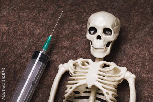 Human skeleton and syringe on a stone, top view. Lethal injection ...