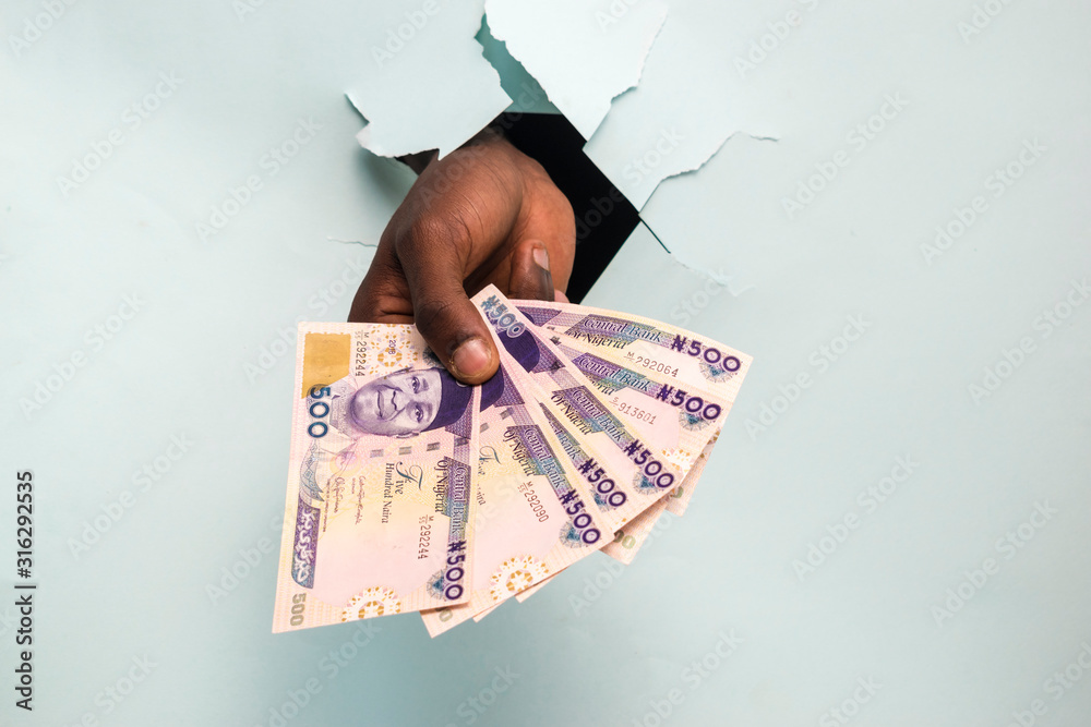 hand of a black person through a tear in a cardboard paper holding some ...