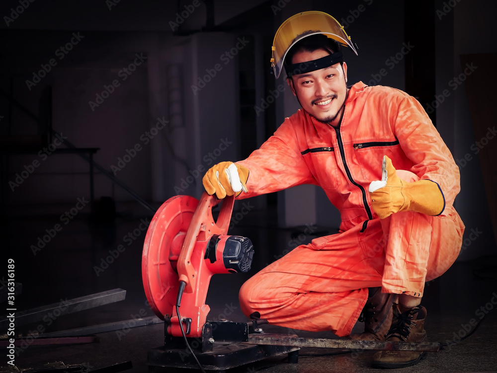 male worker wearing orange jumpsuit and safety mask sitting in workshop ...