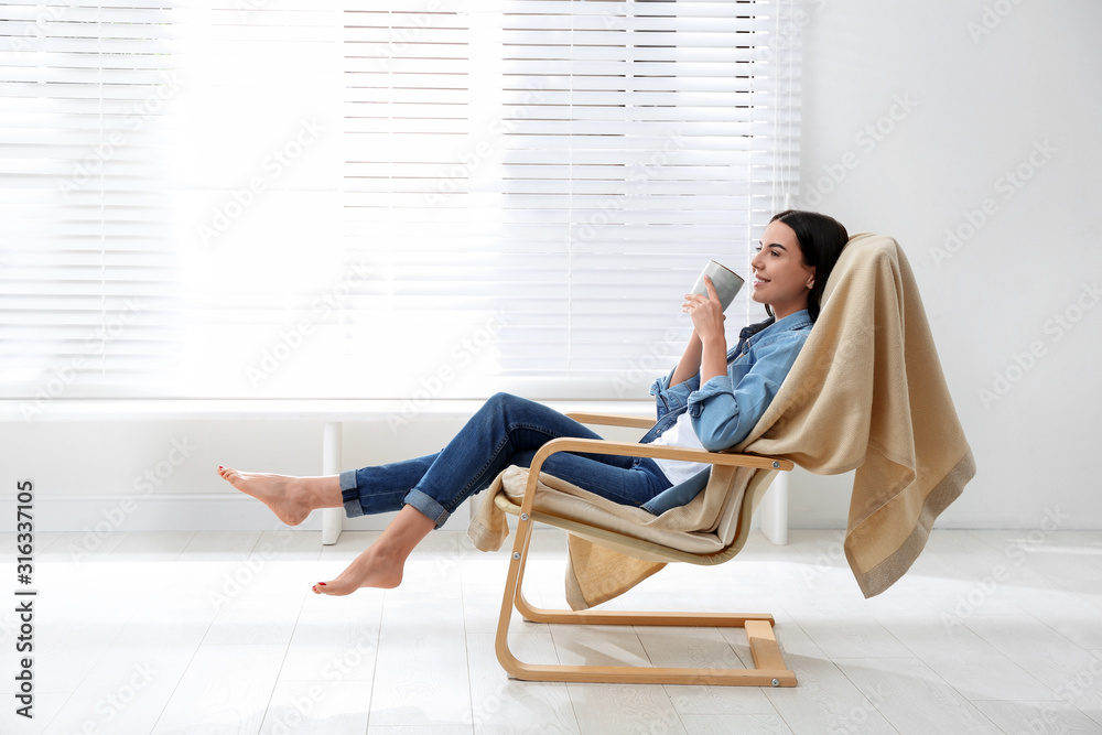Young woman relaxing in armchair near window at home Stock Photo ...