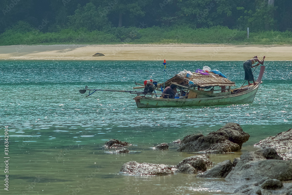 view of Moken's boat floating seaside in blue-green sea with green ...