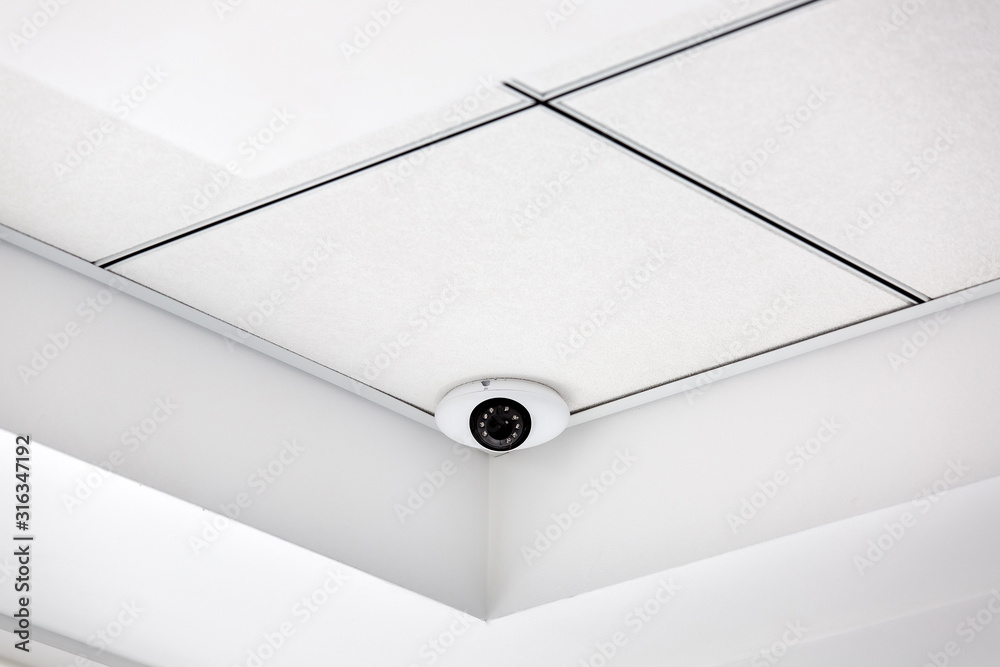CCTV camera in the corner on a white suspended ceiling, security system ...