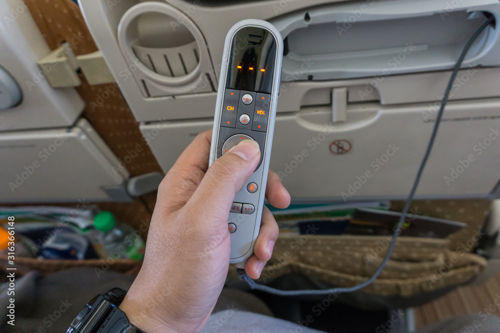 Passenger man hand holding remote control of airplane Entertainment on ...