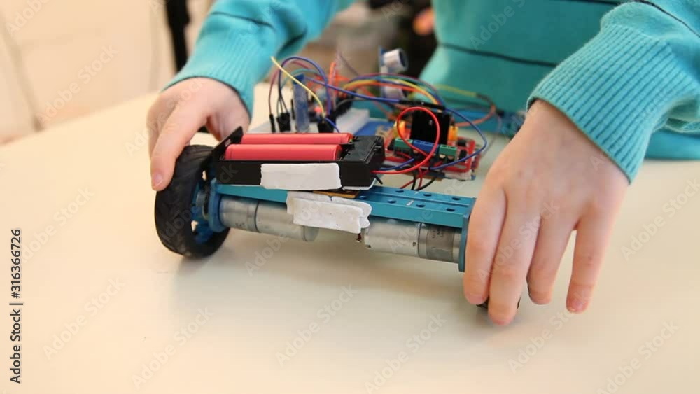 Robotics technology and STEM education class concept: Boy adjusts his ...