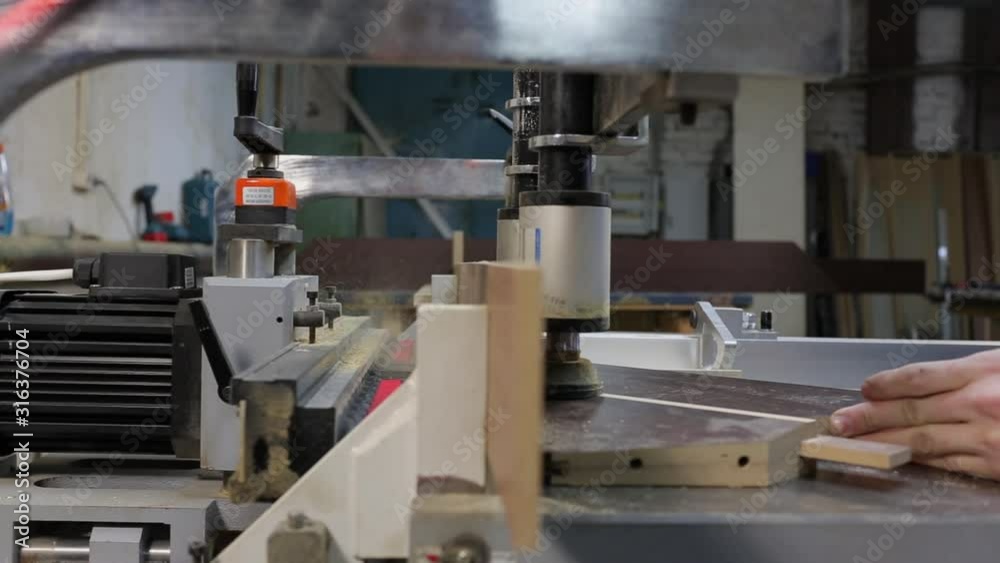 At factory for production of wooden furniture, machine works, drills ...
