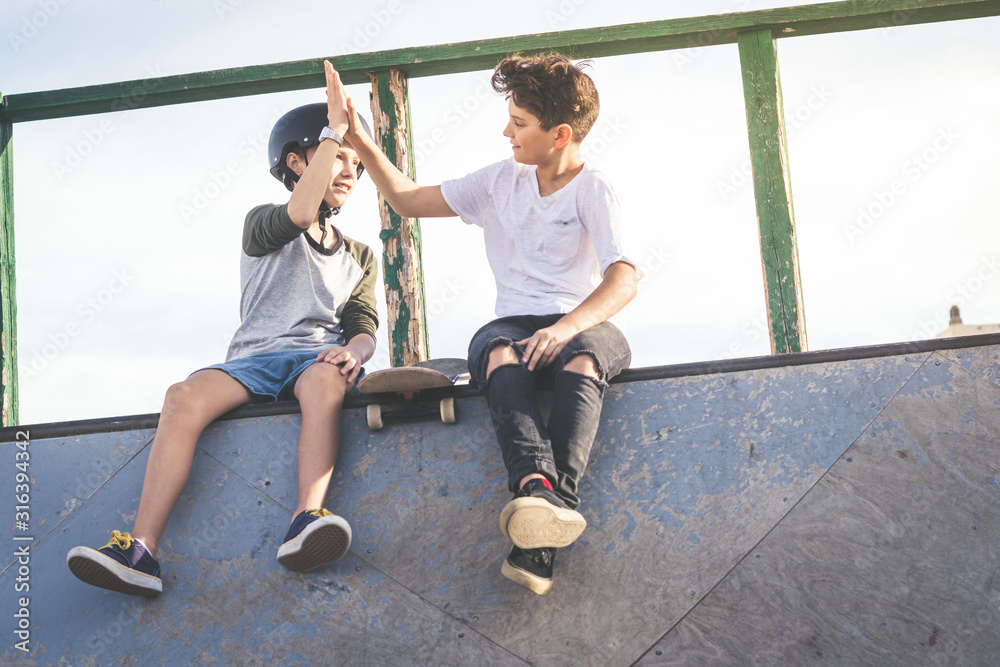 Two young boys hit high five after nice tricks and jumps at the ...