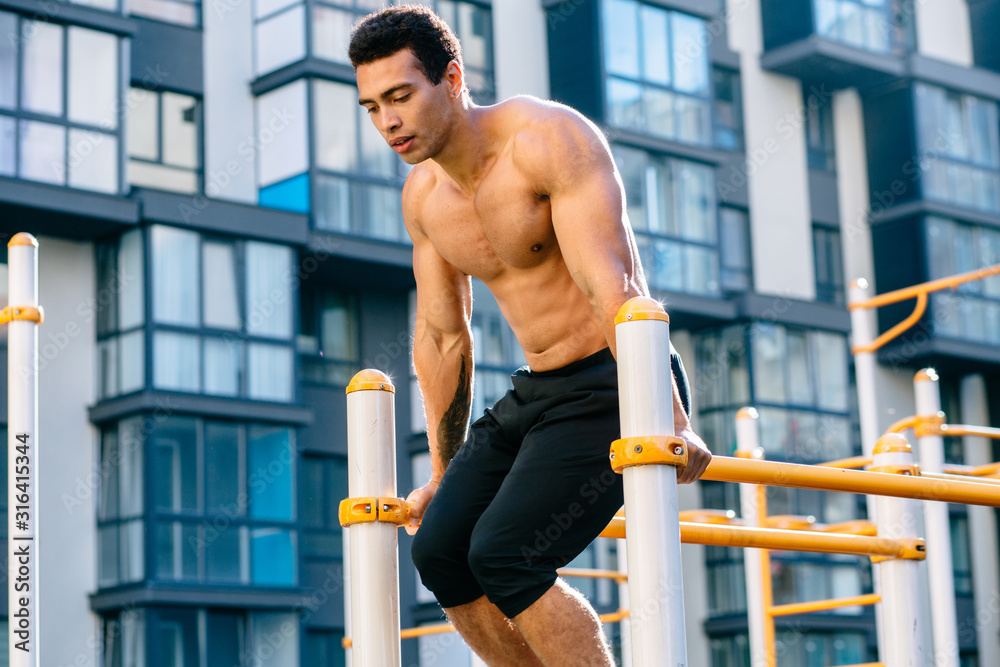 Portrait of athlete young mixed race man doing exercises on horizontal ...