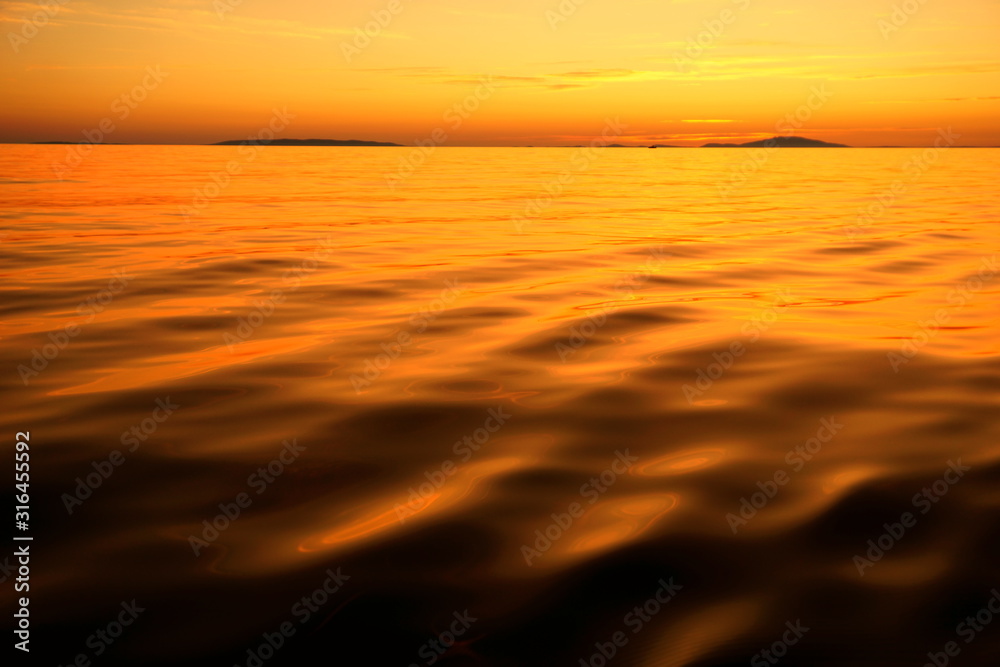 Vivid orange color sunset with unreal colorful water surface and sky ...