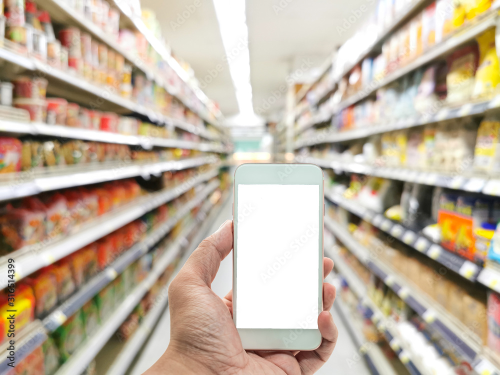 Hand holding smart phone or mobile phone on convenience store shelves ...