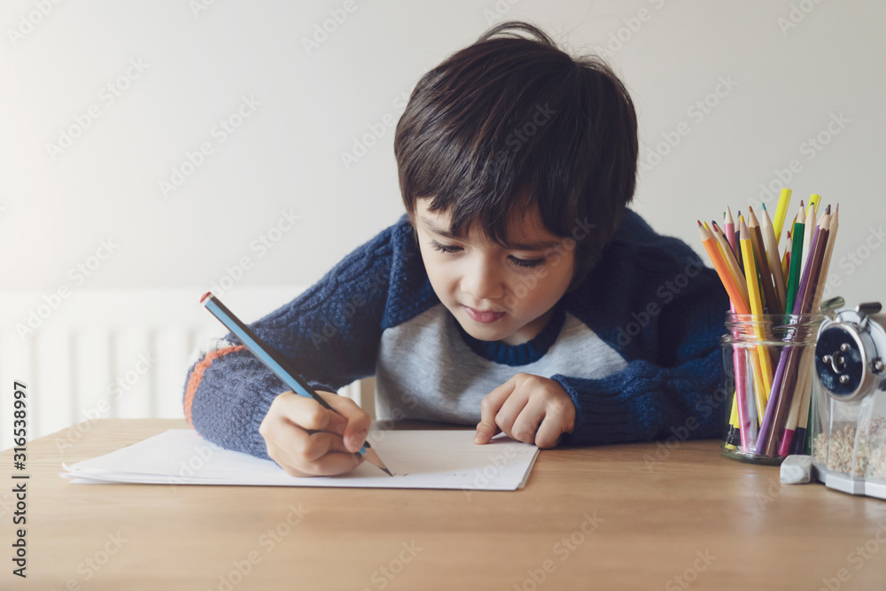 Portrait of school kid boy siting on table doing homework, Happy Child ...