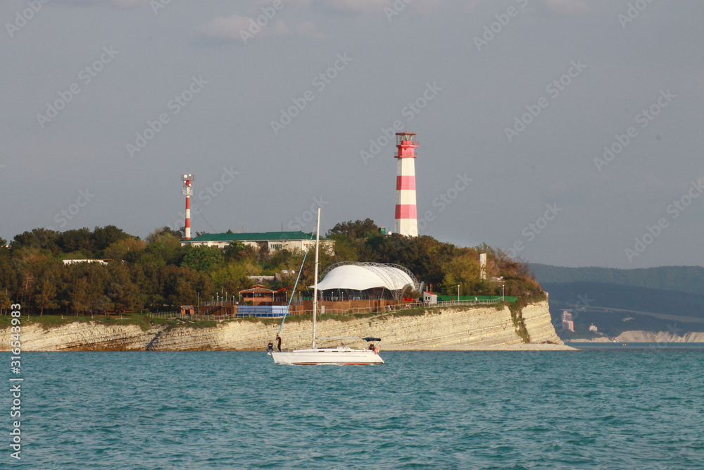 Coastal lighthouse on the edge of a rocky promontory in the black sea ...