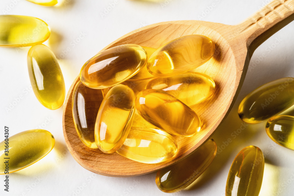 Omega 3 yellow capsules in wooden spoon on white background. EPA and ...