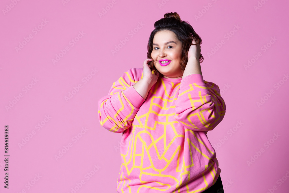 Happy plus size model in casual clothes, fat woman on pink background ...