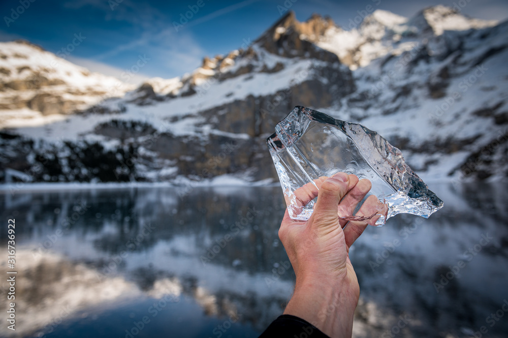 hand holding a beautiful clear chunk of ice on frozen lake Oeschinensee ...
