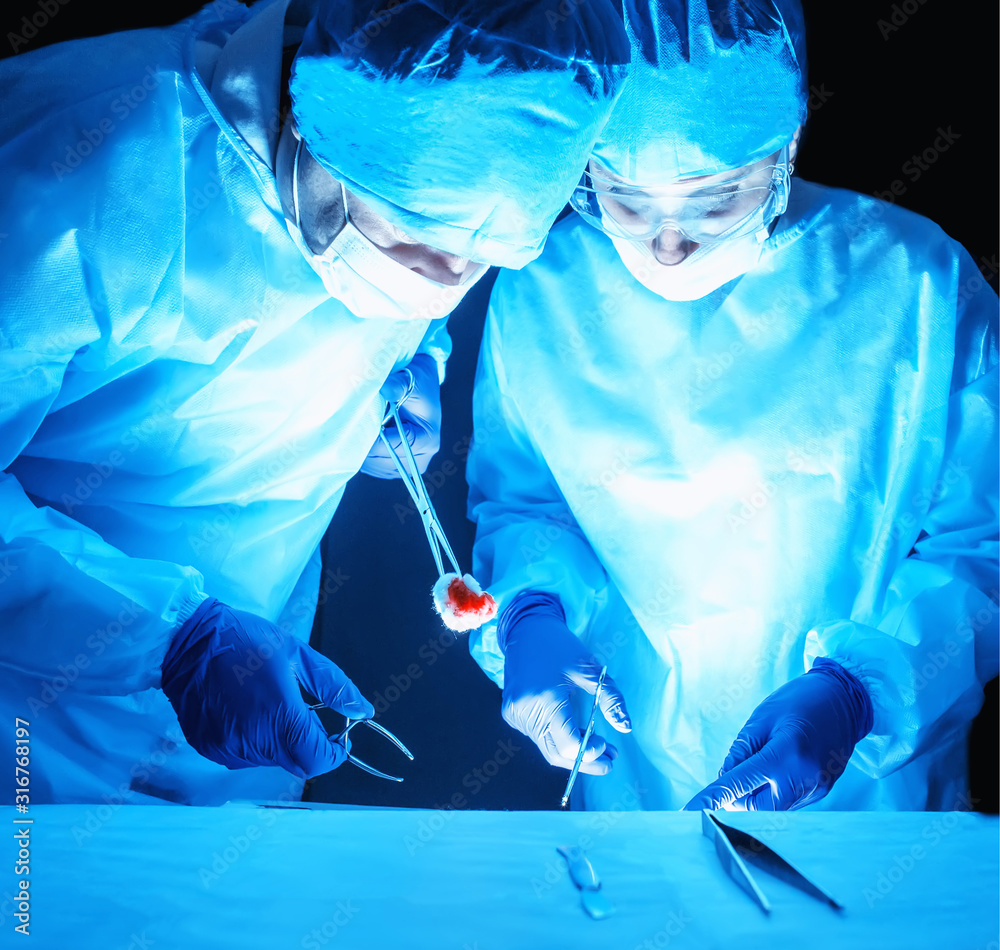 Two surgeons perform a complex operation to remove a cancer tumor ...
