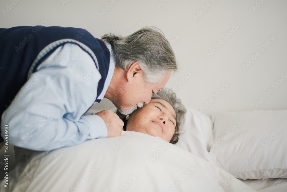 Senior Asian couple love lying on the bed. Retired man take care by ...