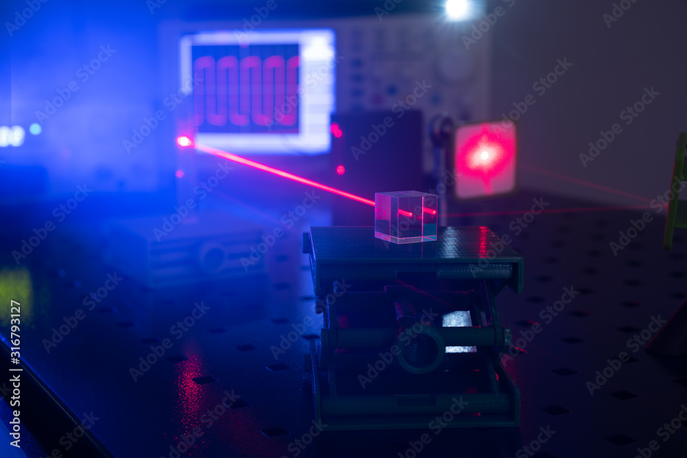 Experiment in optic lab with laser device. Red laser on optical table ...