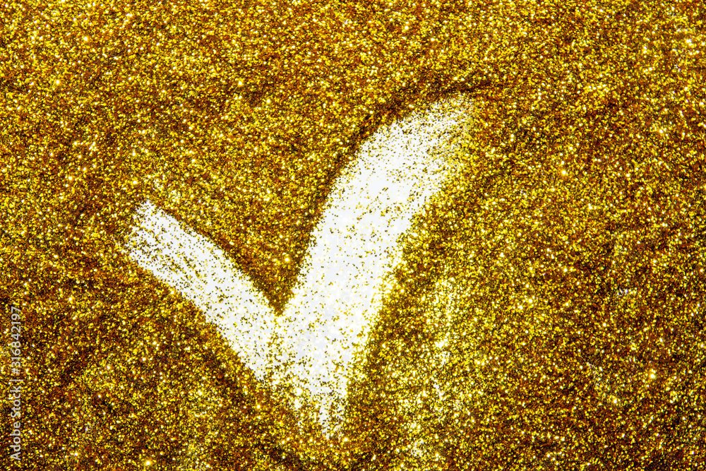 Drawing a check mark on the golden sand glitter. Check mark against a ...