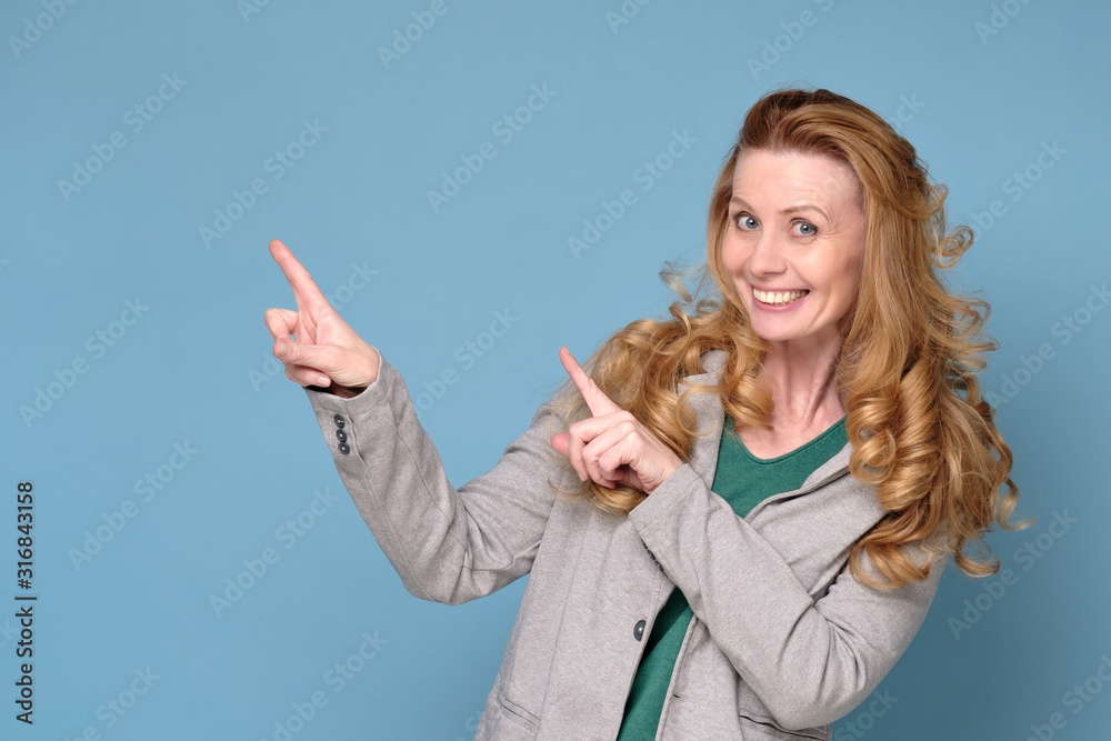 Mature woman with long hair pointing with finger pointing aside. Studio ...