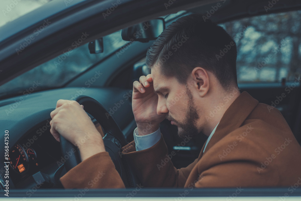 a young man of thirty years, holding his head, having a headache ...