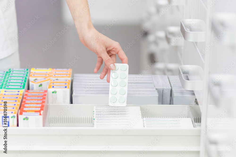 Pharmacist holding medicine box and capsule pack in pharmacy drugstore ...