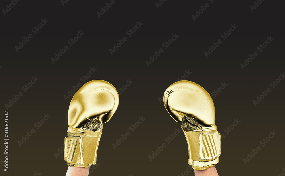 Gold boxing gloves raised up against a dark background. Victory concept ...