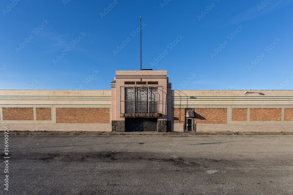 Exterior front of a long abandoned brick retail building with empty ...