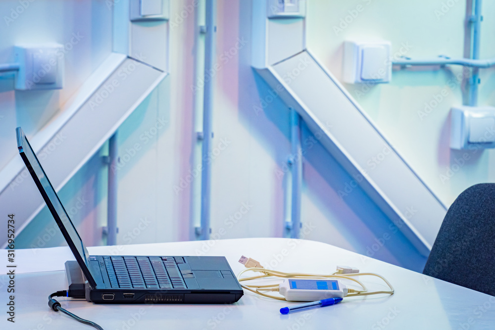A laptop next to an electric tester. Working devices electrician on a ...