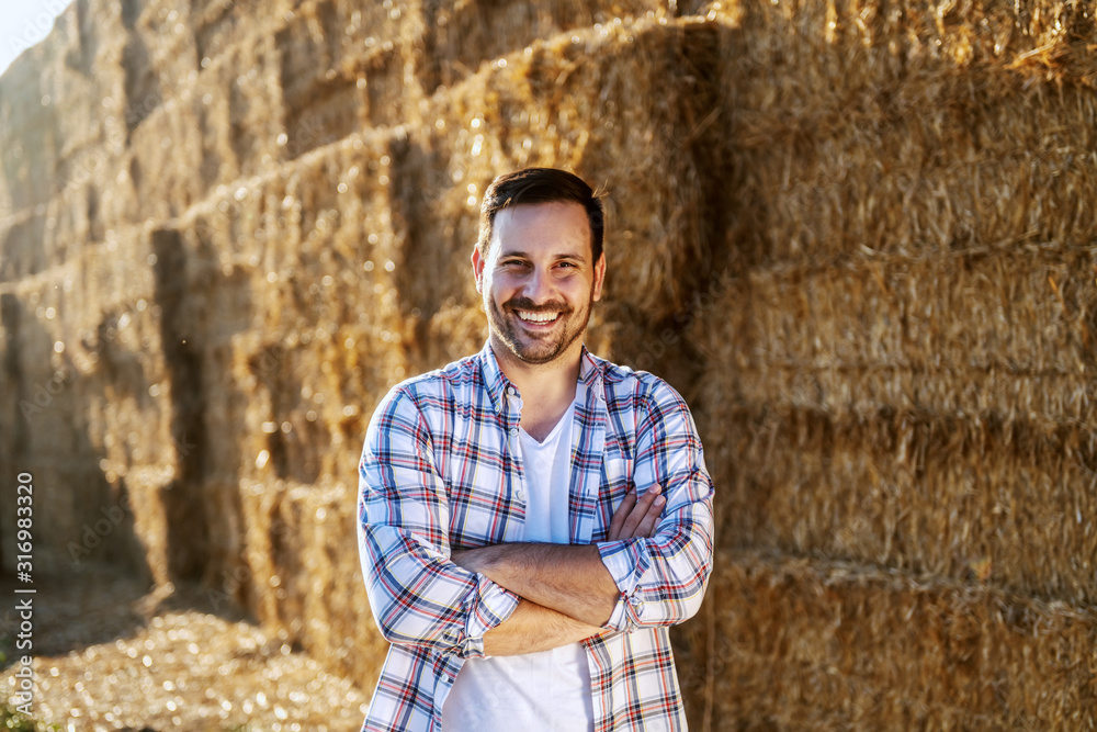 Handsome caucasian smiling farmer standing outdoors with arms crossed ...