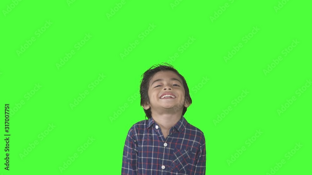 Cute little boy smiling at the camera while standing in the studio ...