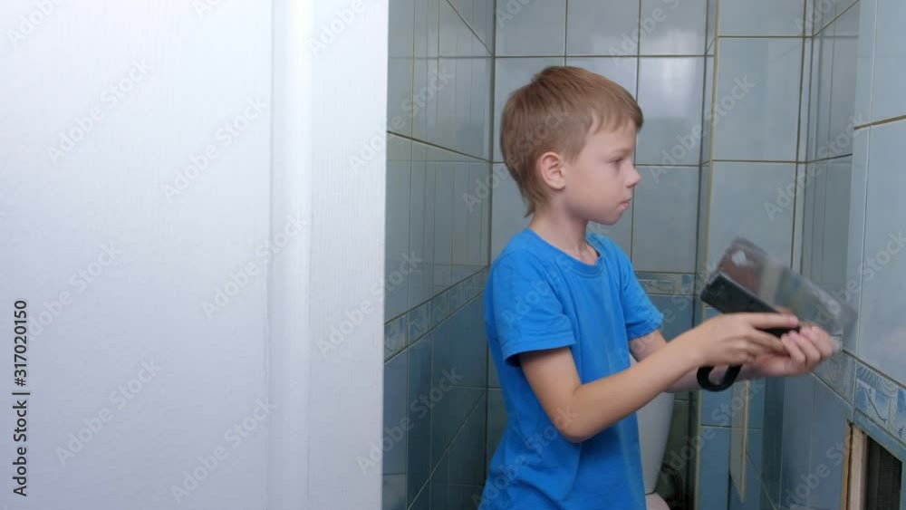 Portrait of child boy tiler makes renovation repair at home, he removes ...