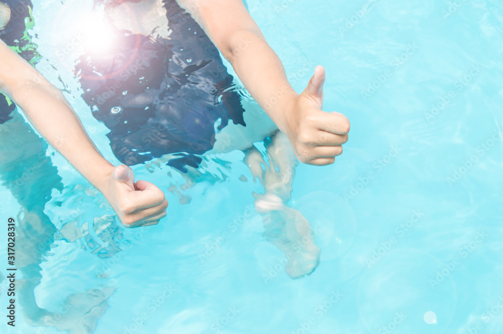 Thumbs up two teenage girls with long hair in swimsuits in a pool with ...