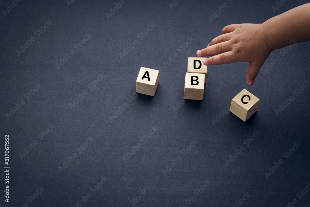 Wooden alphabet cube with words ABCD closeup and children hands on ...