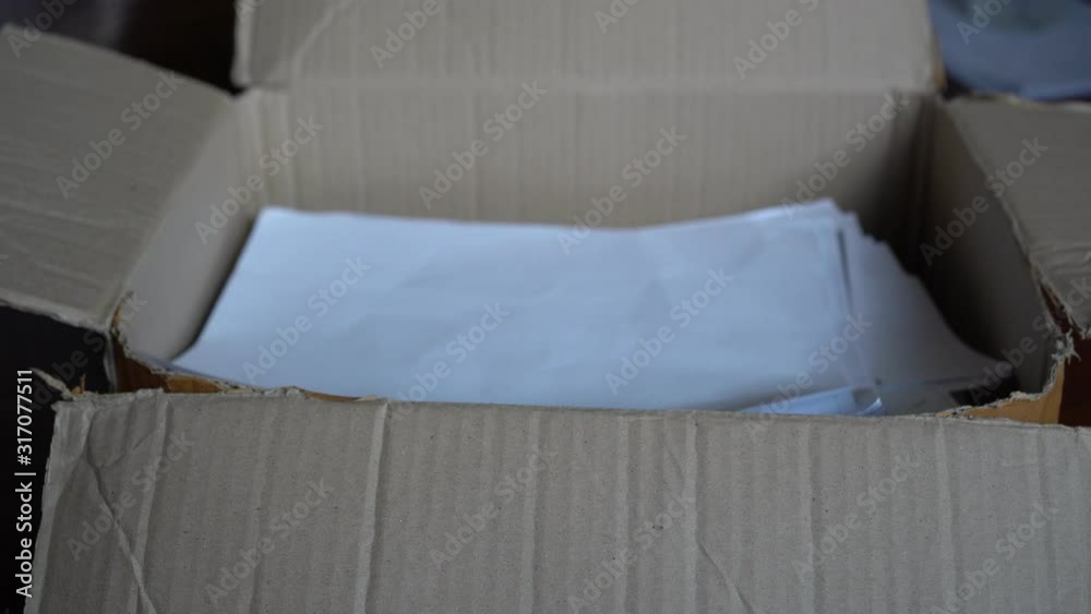 Putting a heap of used paper into a cardboard box Stock Video | Adobe Stock
